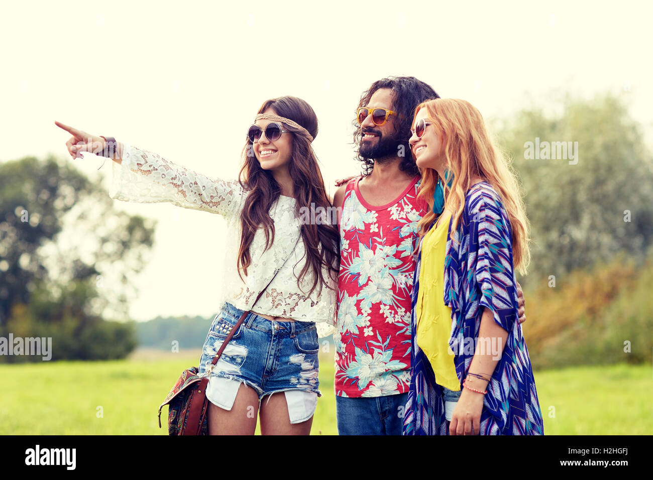 smiling young hippie friends on green field Stock Photo - Alamy