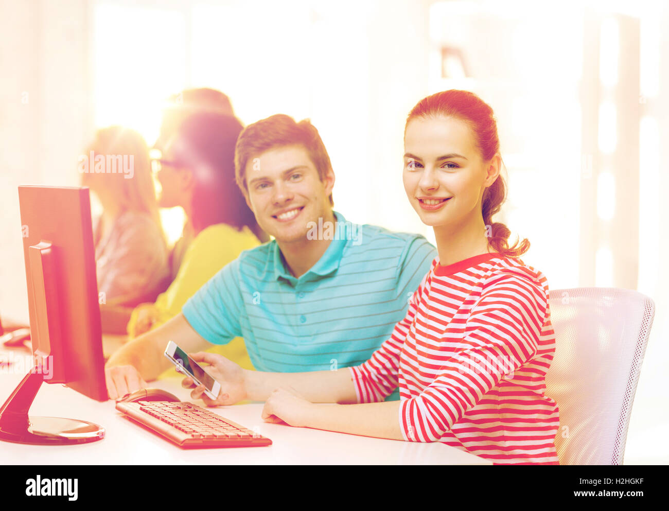 smiling student with smartphone in computer class Stock Photo - Alamy
