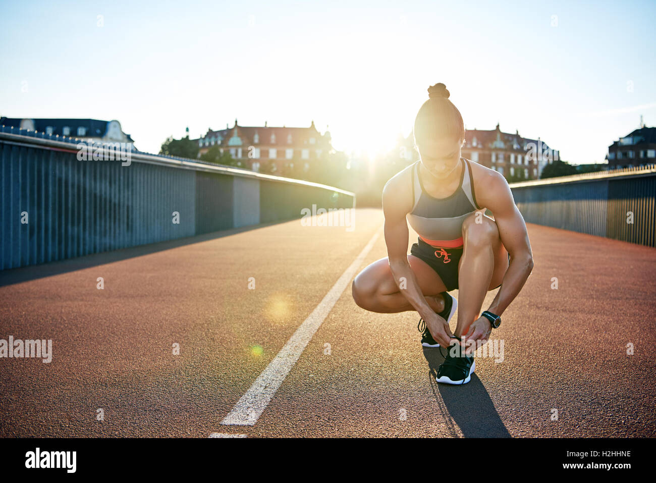 Female runner tying shoes on bridge hi-res stock photography and images ...
