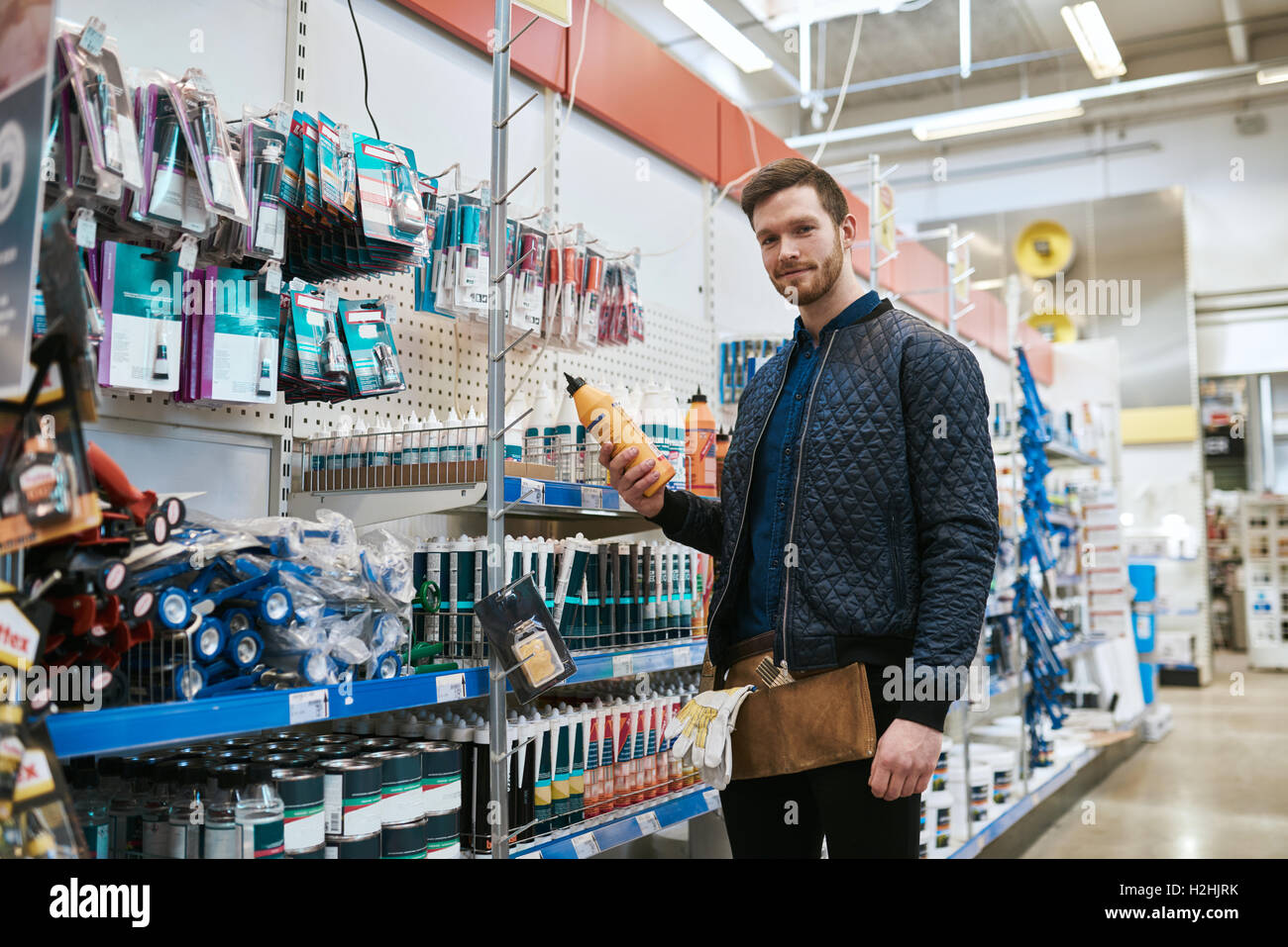 Young handyman shopping in a hardware store standing looking down at ...