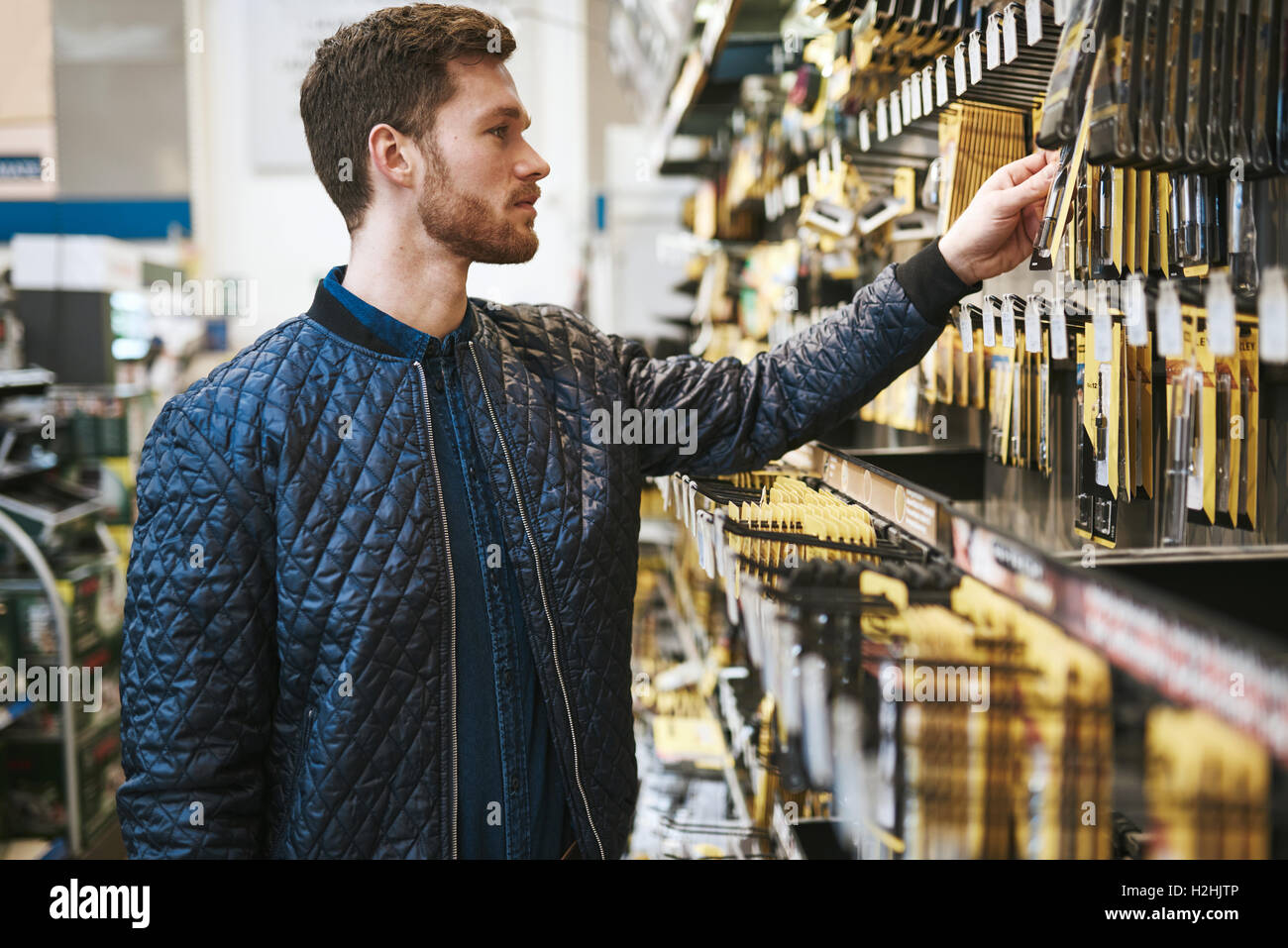Bearded young man in a hardware store standing reading the information ...