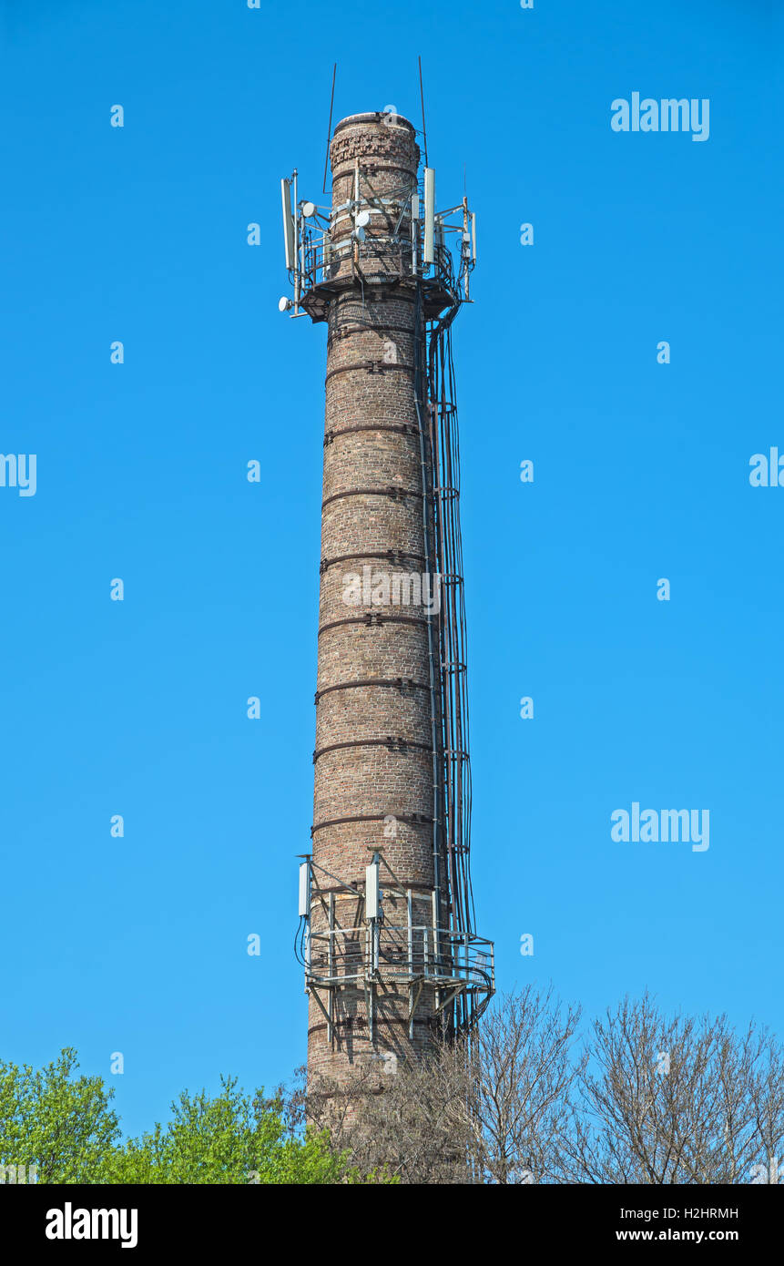 Brick flue with connected repeaters in an industrial area on the sky ...