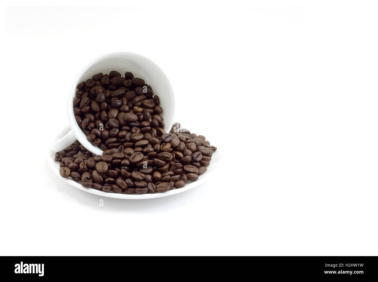 Fried brown coffee beans spilled out of white cup isolated on white ...