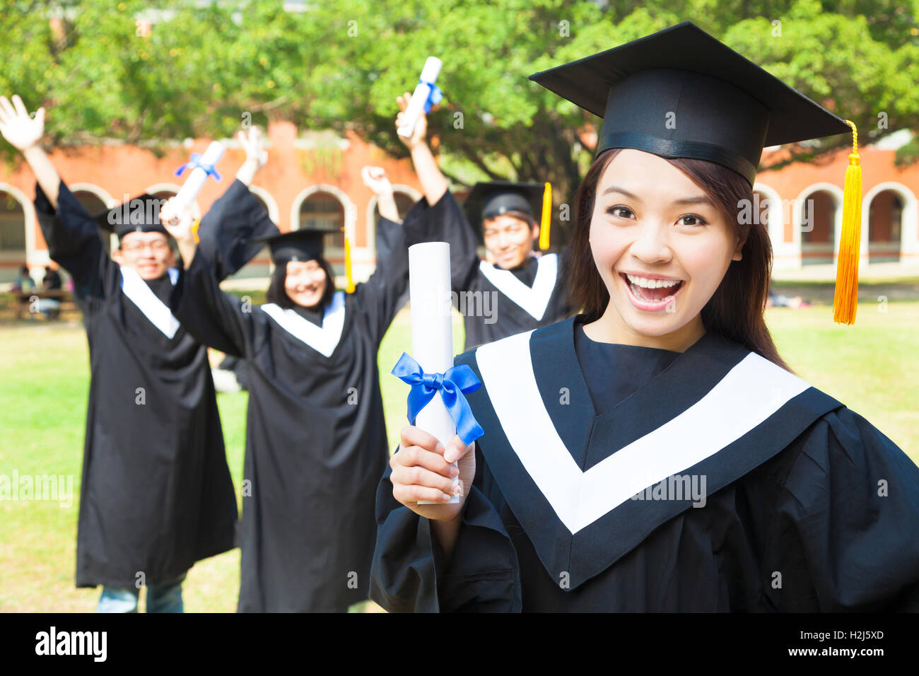 happy college graduate holding a diploma with friends Stock Photo - Alamy