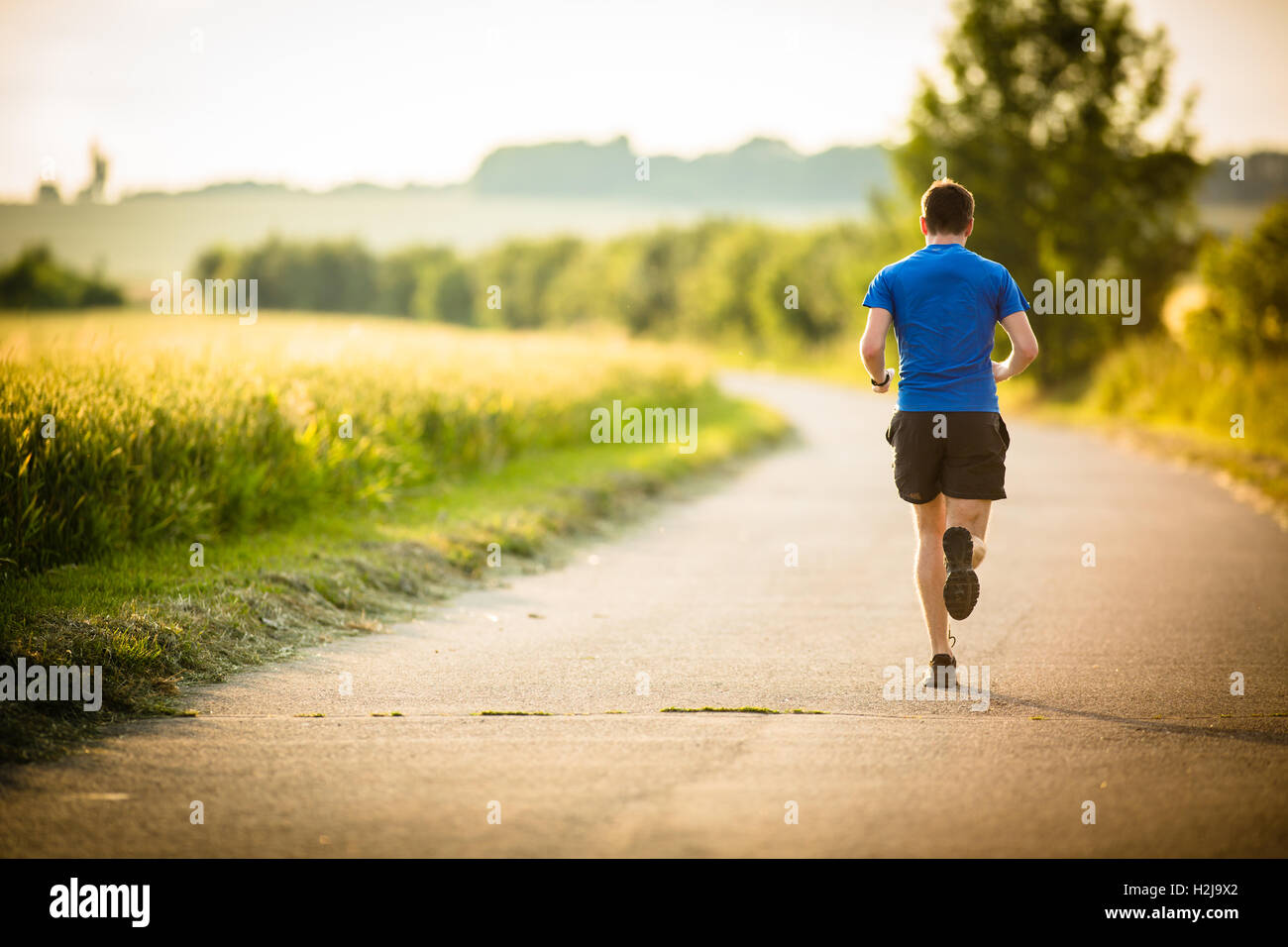 Male athlete/runner running on road Stock Photo - Alamy
