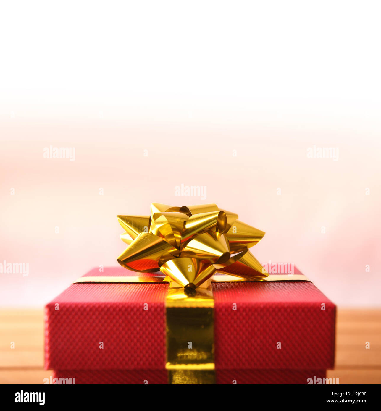 Red gift box with golden ribbon closeup and light background. Front ...