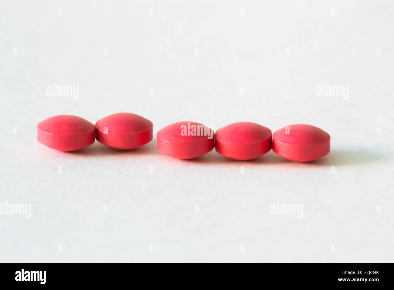 Five red pills on white background. Medicine Stock Photo - Alamy