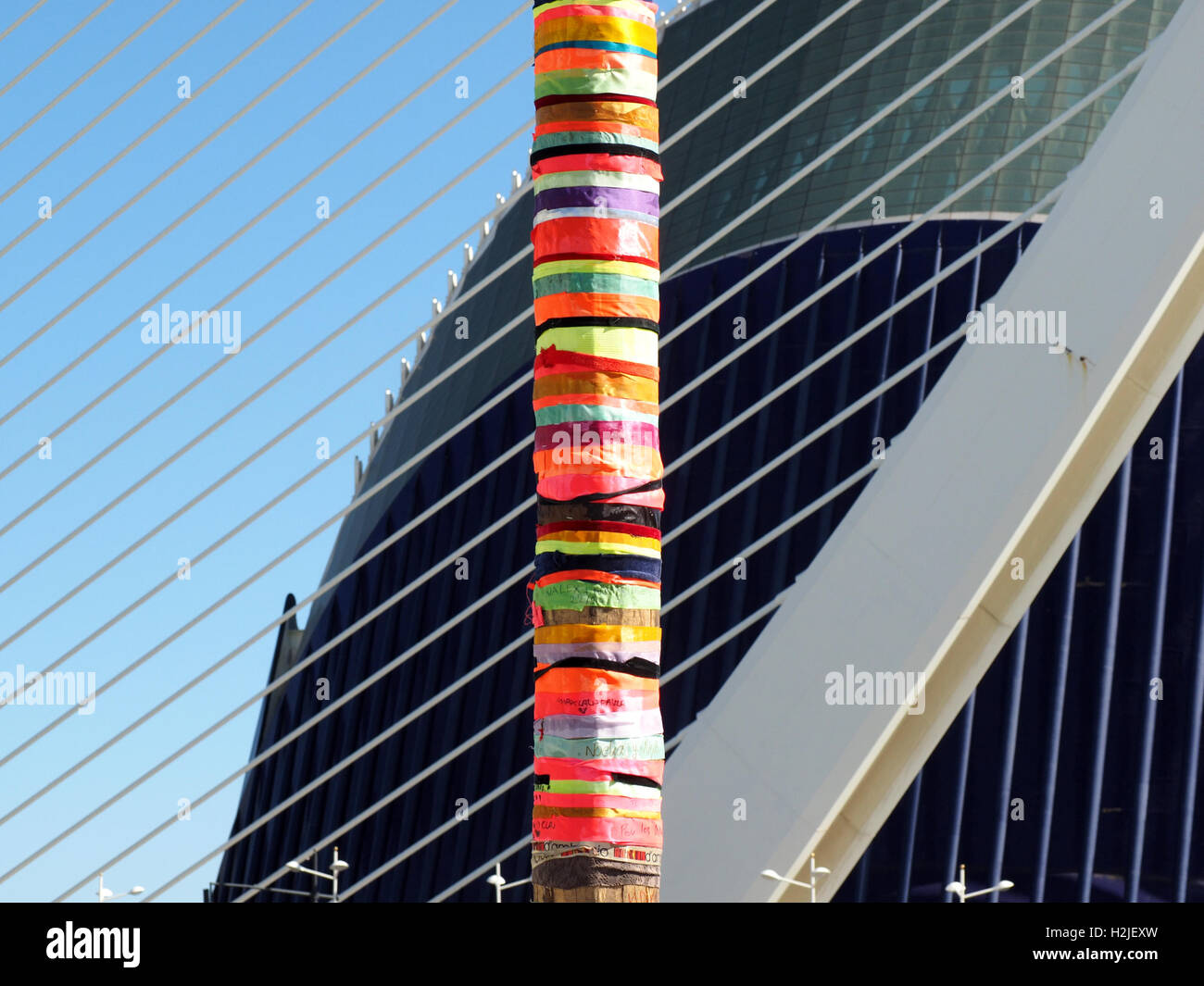 brightly coloured pole against white concrete beam and diagonal cables ...