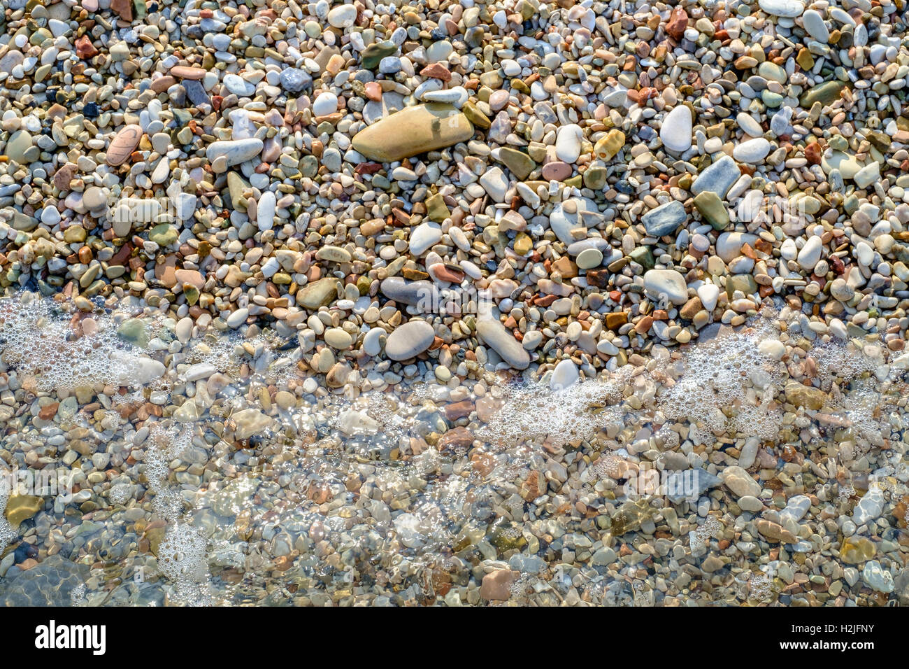 Pebbly beach and little wave background Stock Photo - Alamy