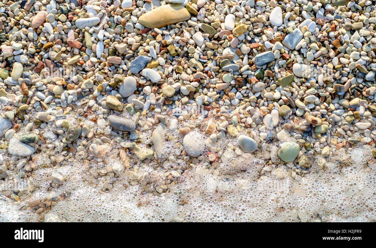 Pebbly beach and little wave background Stock Photo - Alamy