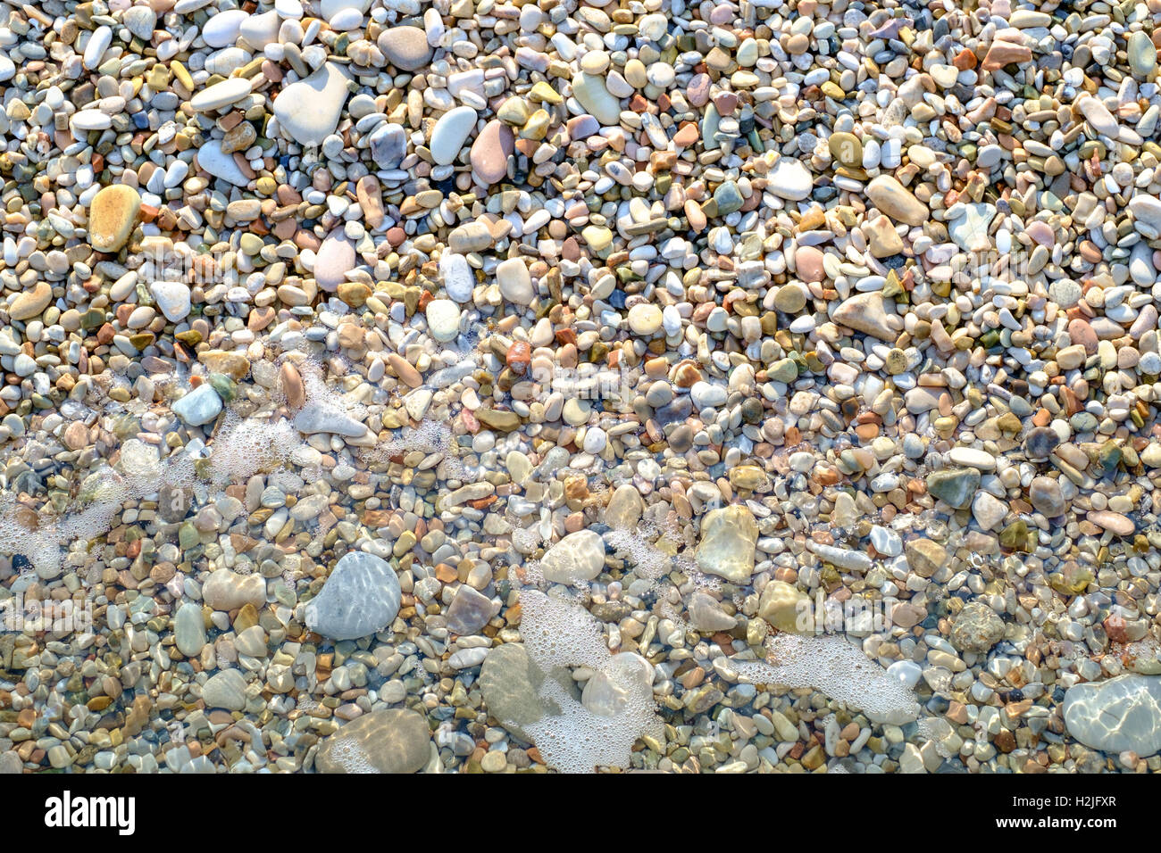 Pebbly beach and little wave background Stock Photo - Alamy
