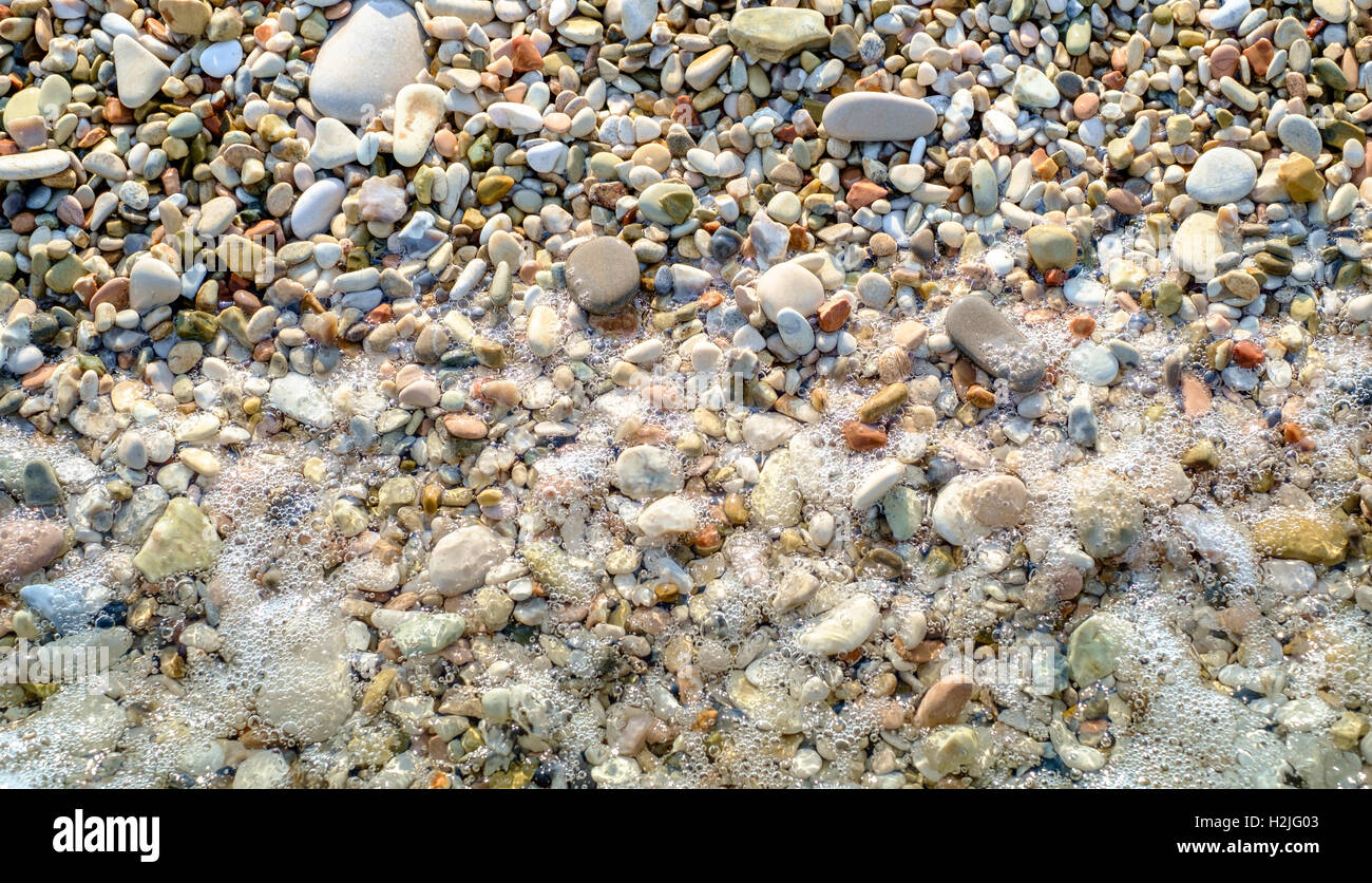Pebbly beach and little wave background Stock Photo - Alamy