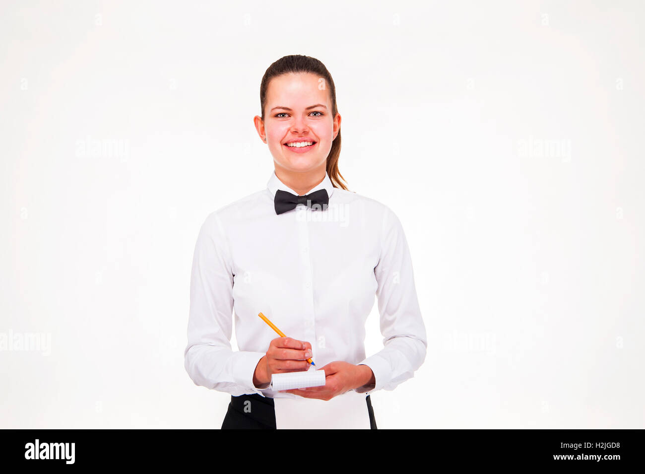 Young woman in waiter uniform holding notepad over white background ...