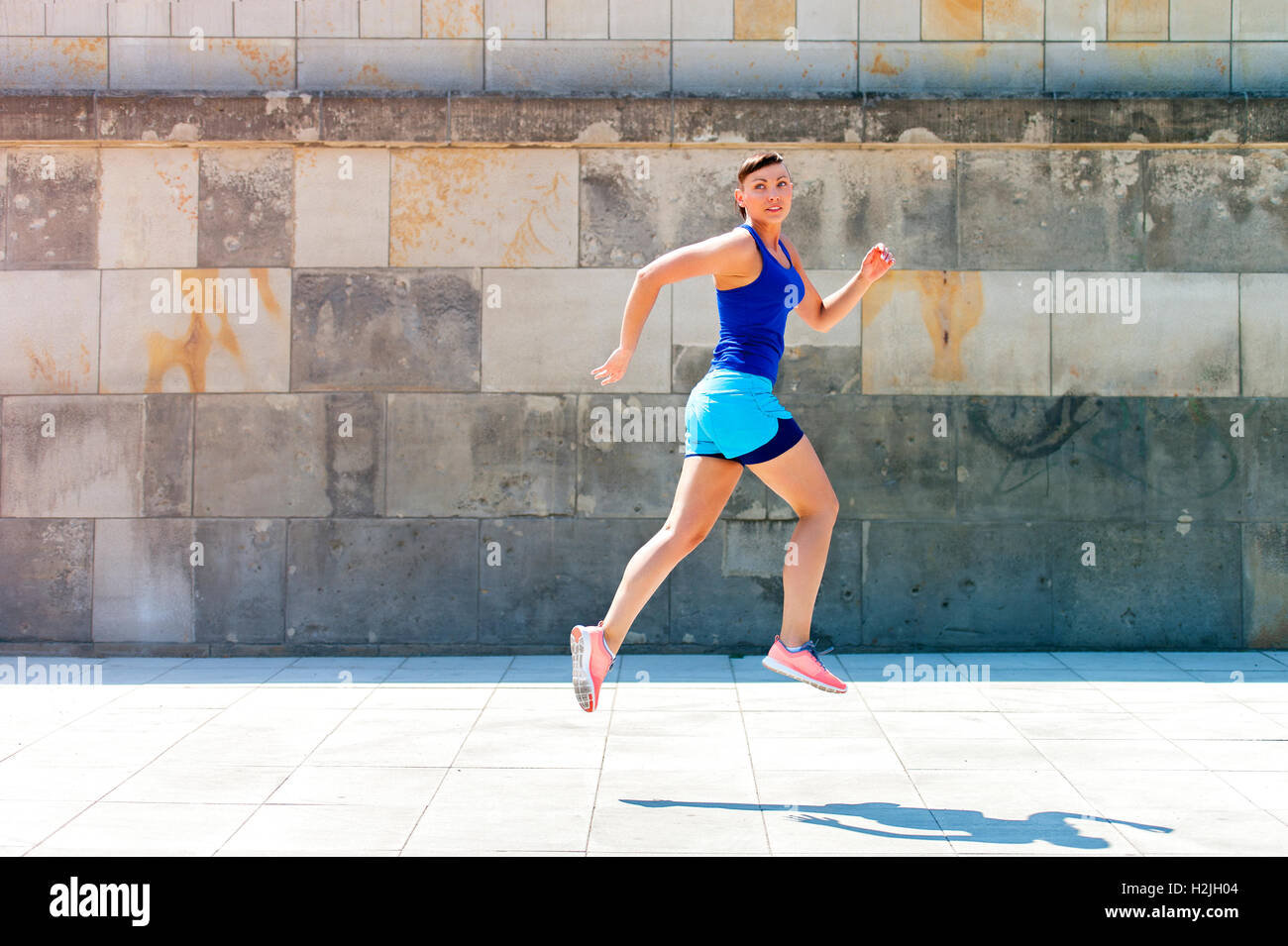 Jogger woman jump by the wall in city Stock Photo - Alamy
