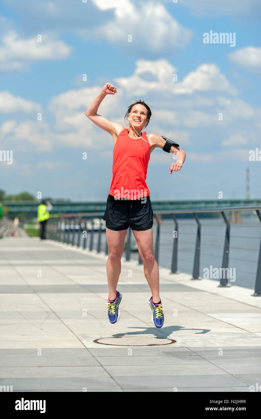 Jumping fit woman with arms up Stock Photo - Alamy