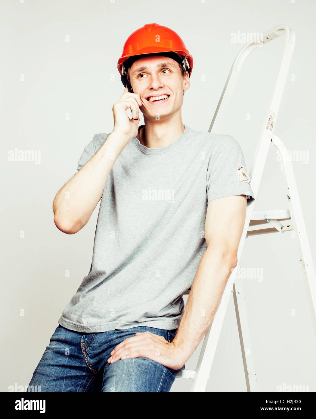 young real hard worker man isolated on white background on ladder ...