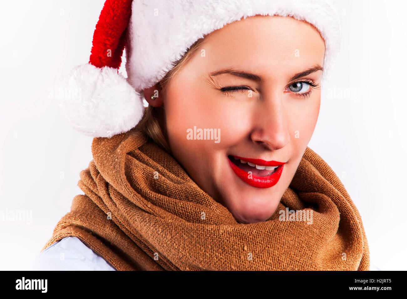Woman in santa hat blinking one eye. Smiling over white background ...