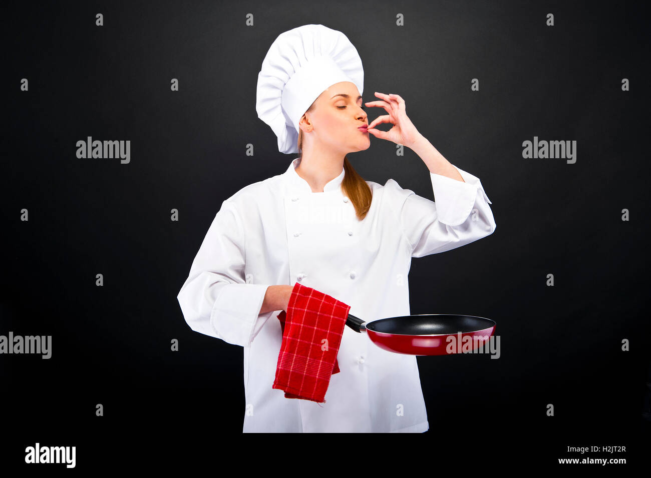 Young female chef kissing her hand to show perfection over dark ...