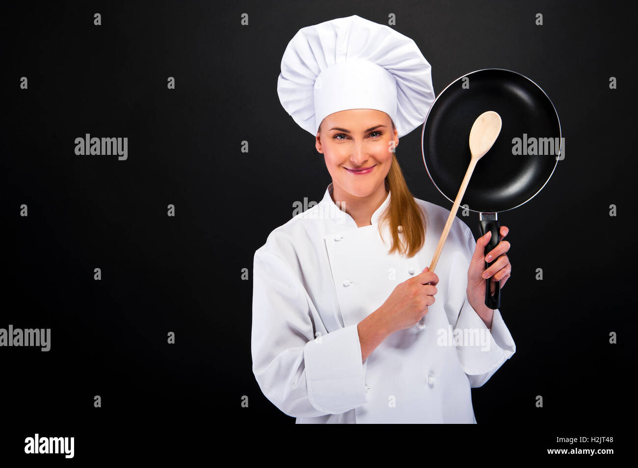 Beautiful blonde woman chef holding pan on white dark background Stock ...