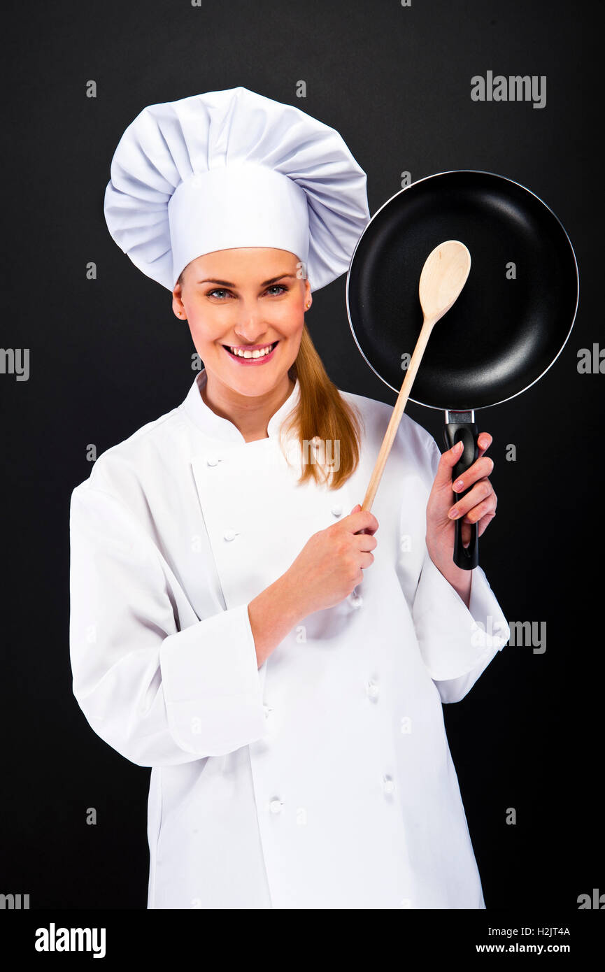 Beautiful blonde woman chef holding pan on white dark background Stock ...