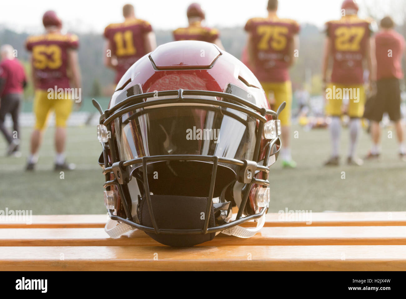 Football helmet on the bench and players behind Stock Photo - Alamy
