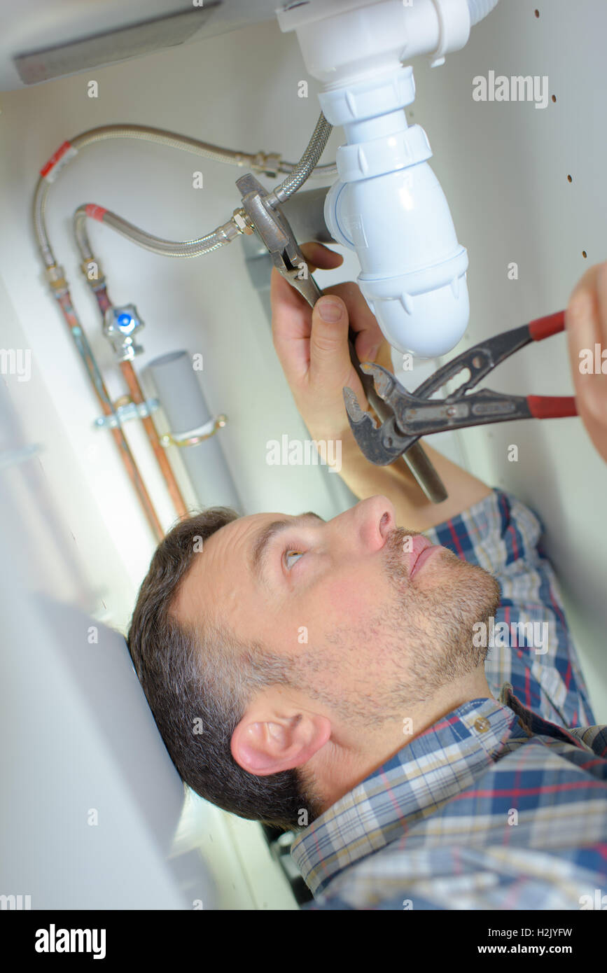 Plumber working under a kitchen sink Stock Photo - Alamy