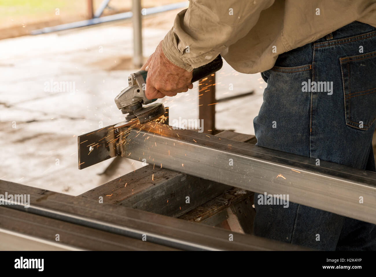 Tradesman fabricating steel stumps for house renovation using a grinder ...
