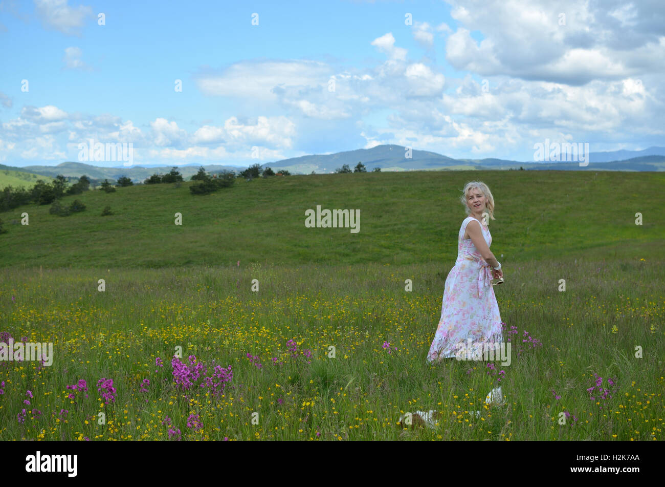 Blonde woman dancing in a meadow in the afternoon Stock Photo - Alamy