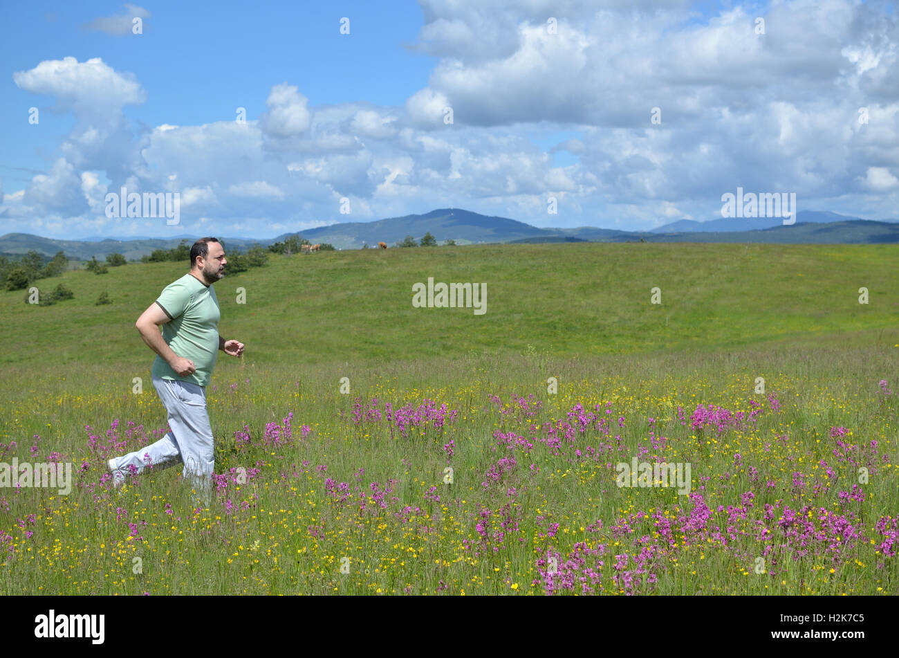 Man running in nature with wildflowers on a cloudy day in springtime ...