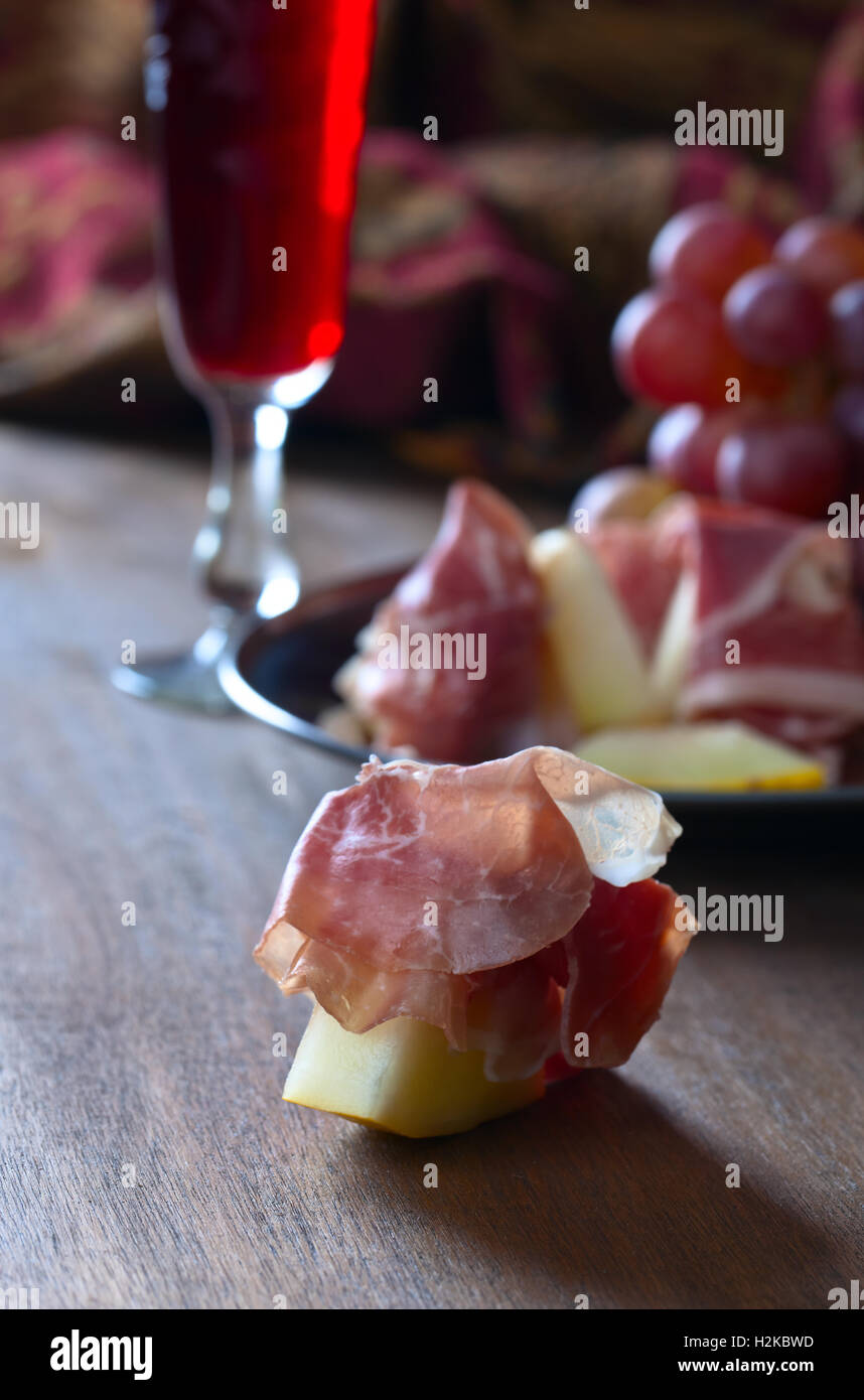 Spanish jamon with melon and grape on wooden table Stock Photo - Alamy