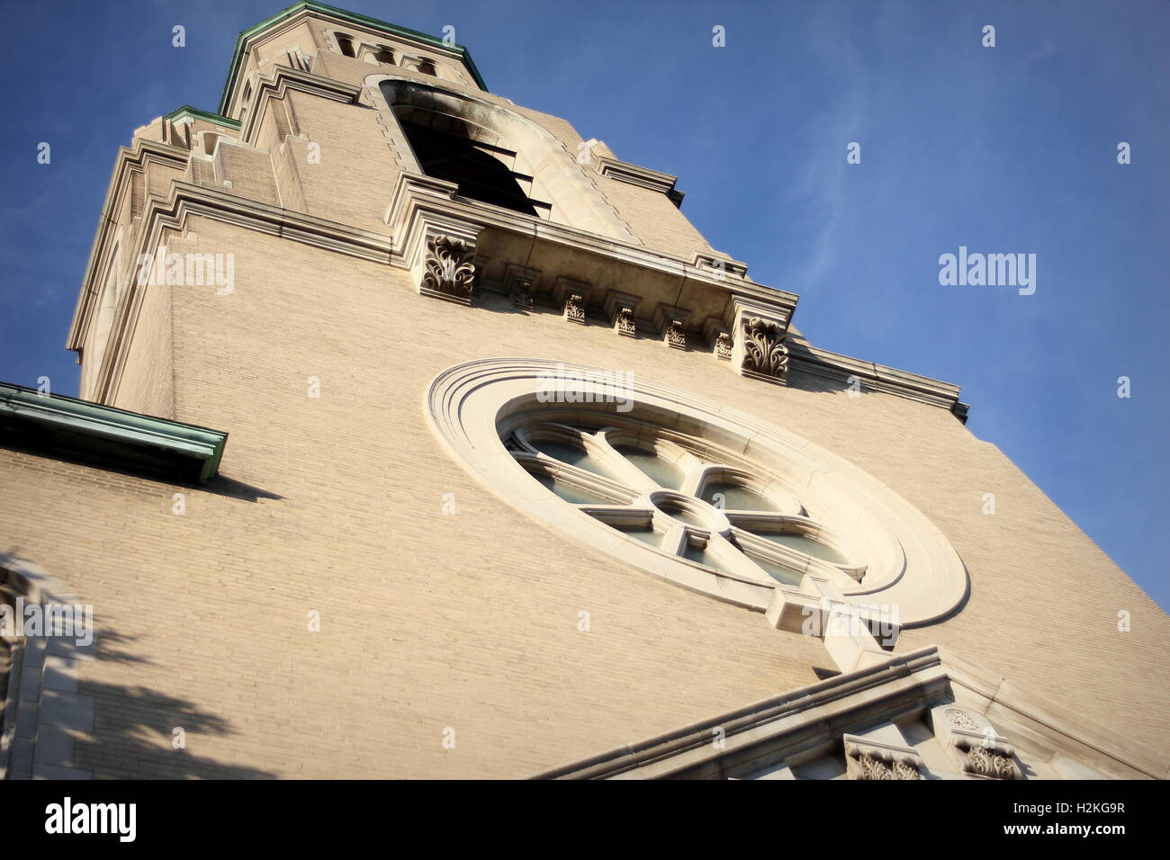 dramatic view of ornate round stained glass window and bell tower st ...
