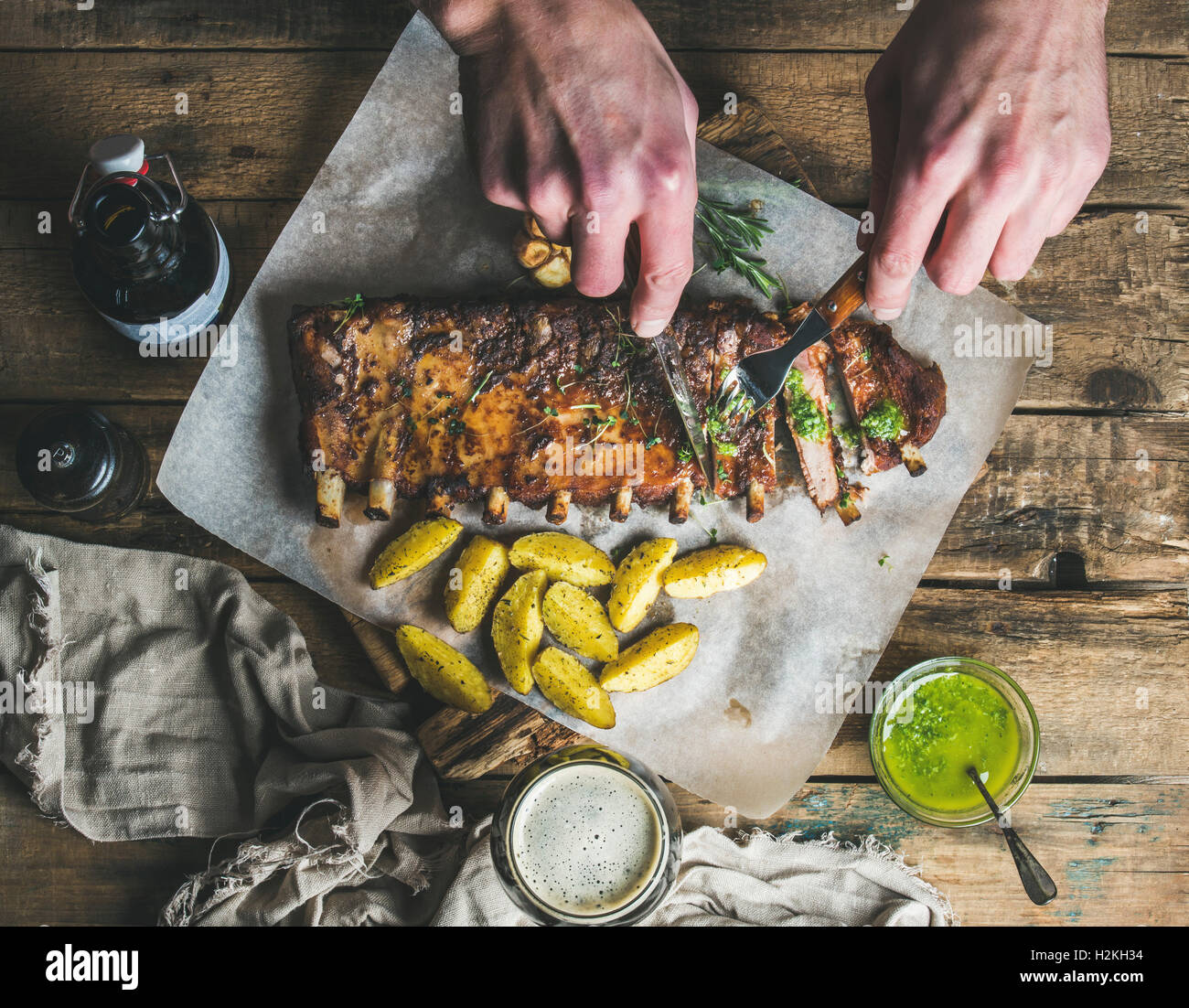 Man eating roasted pork ribs with garlic, rosemary, green herb sauce ...