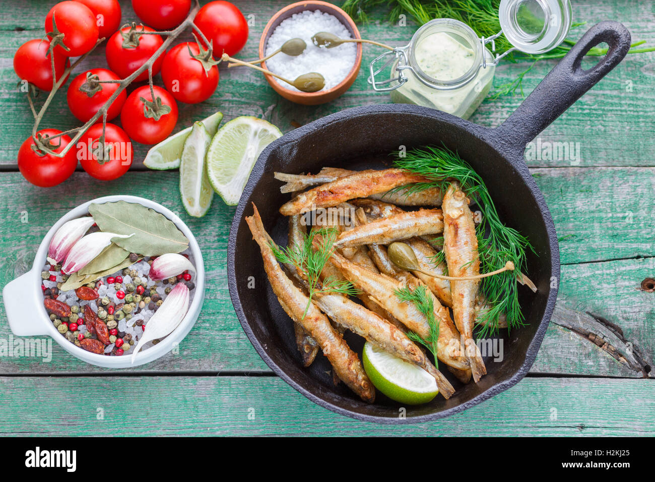 Fried small fish. Fried smelt in the pan on the table with a sauce ...