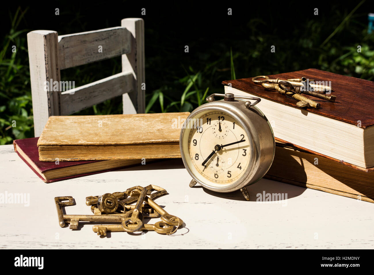 Vintage still life with old alarm clock, keys and books on a white ...