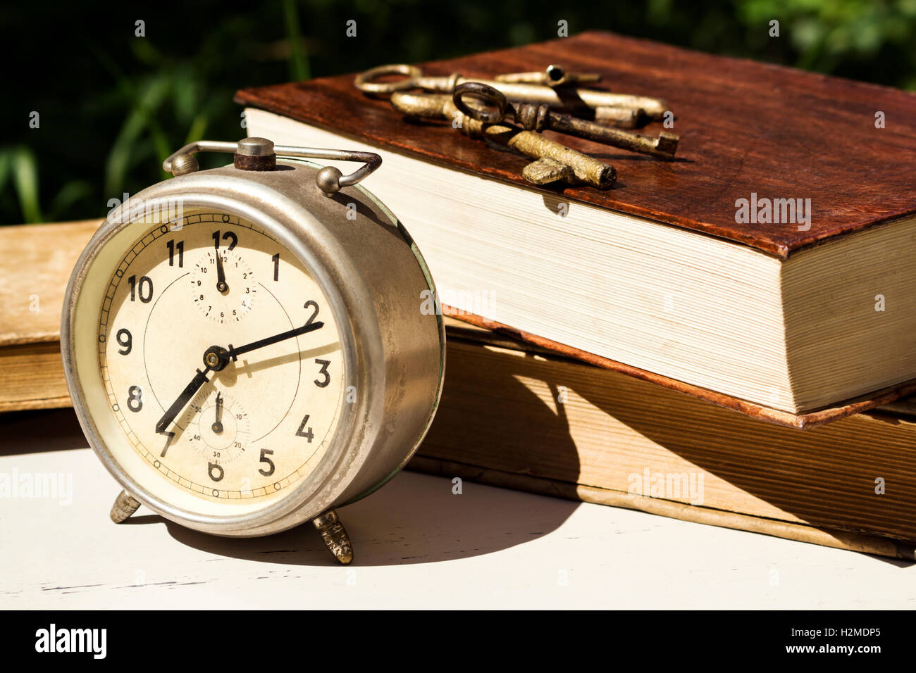 Vintage still life with old alarm clock, keys and books on a white ...
