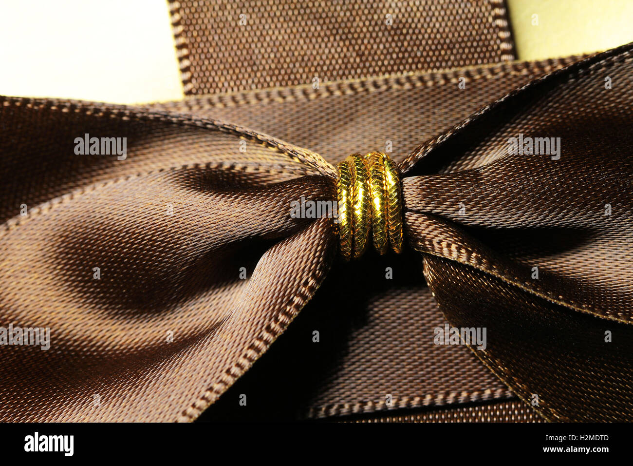 Gift box of golden color with brown ribbon Stock Photo - Alamy