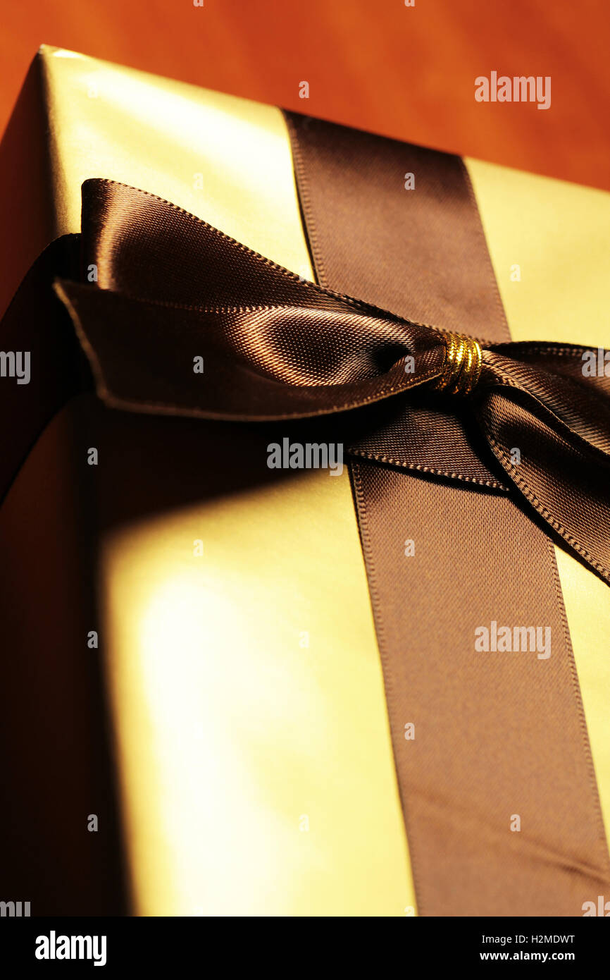 Gift box of golden color with brown ribbon Stock Photo - Alamy