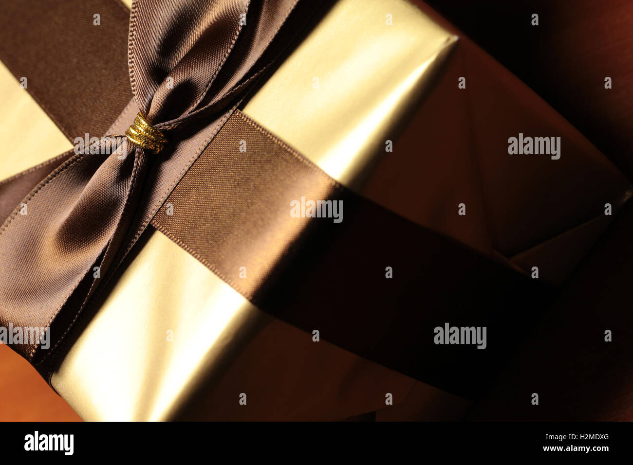 Gift box of golden color with brown ribbon Stock Photo - Alamy