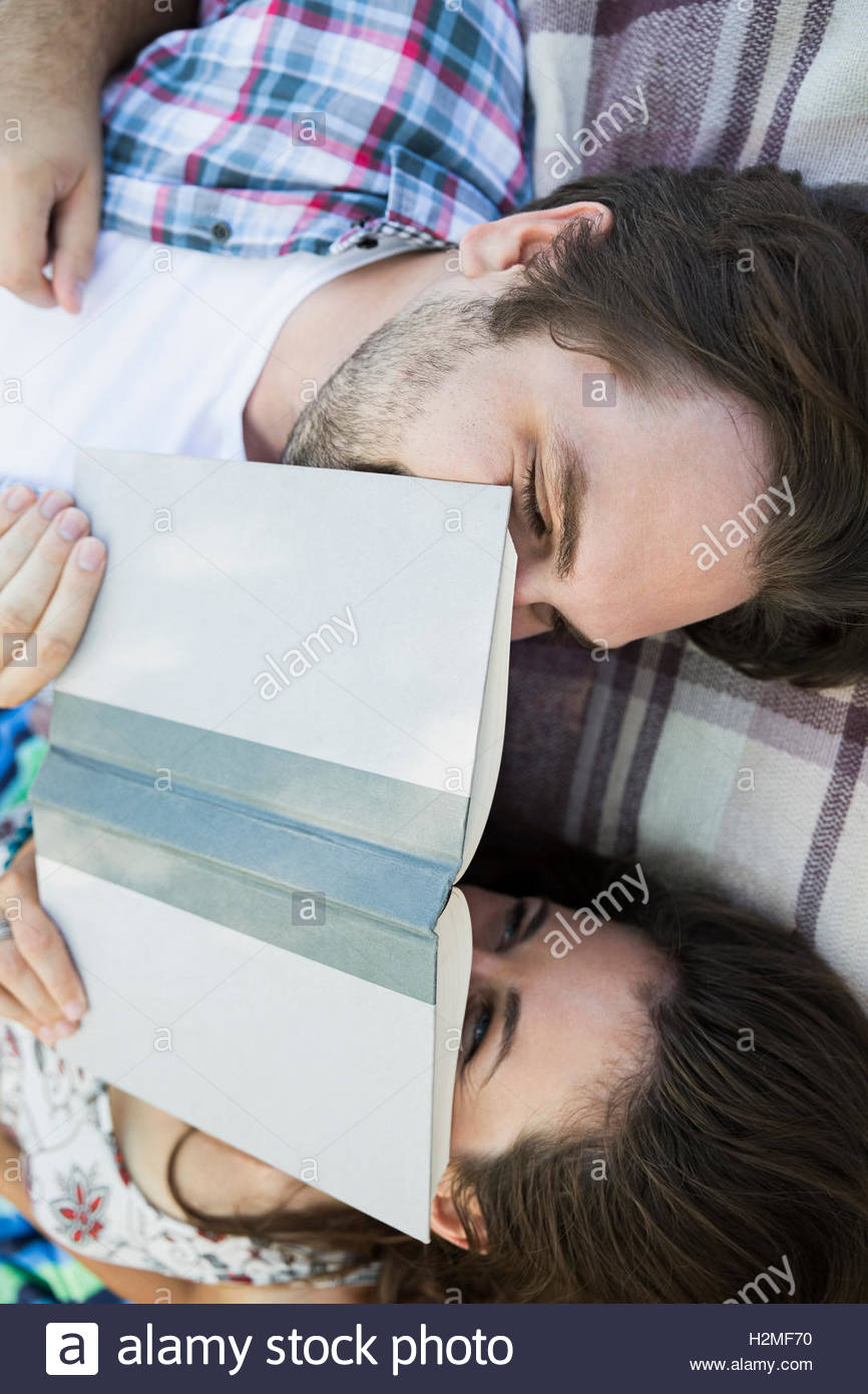 Playful couple hiding reading book Stock Photo - Alamy