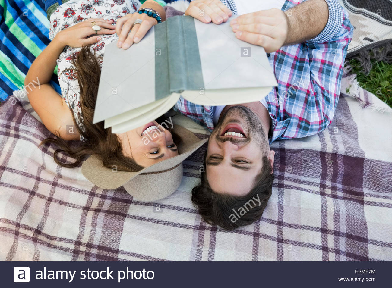 Overhead view couple reading book on blanket in park Stock Photo - Alamy