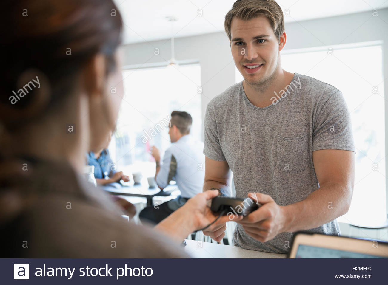 Man using credit card reader at counter in cafe Stock Photo - Alamy