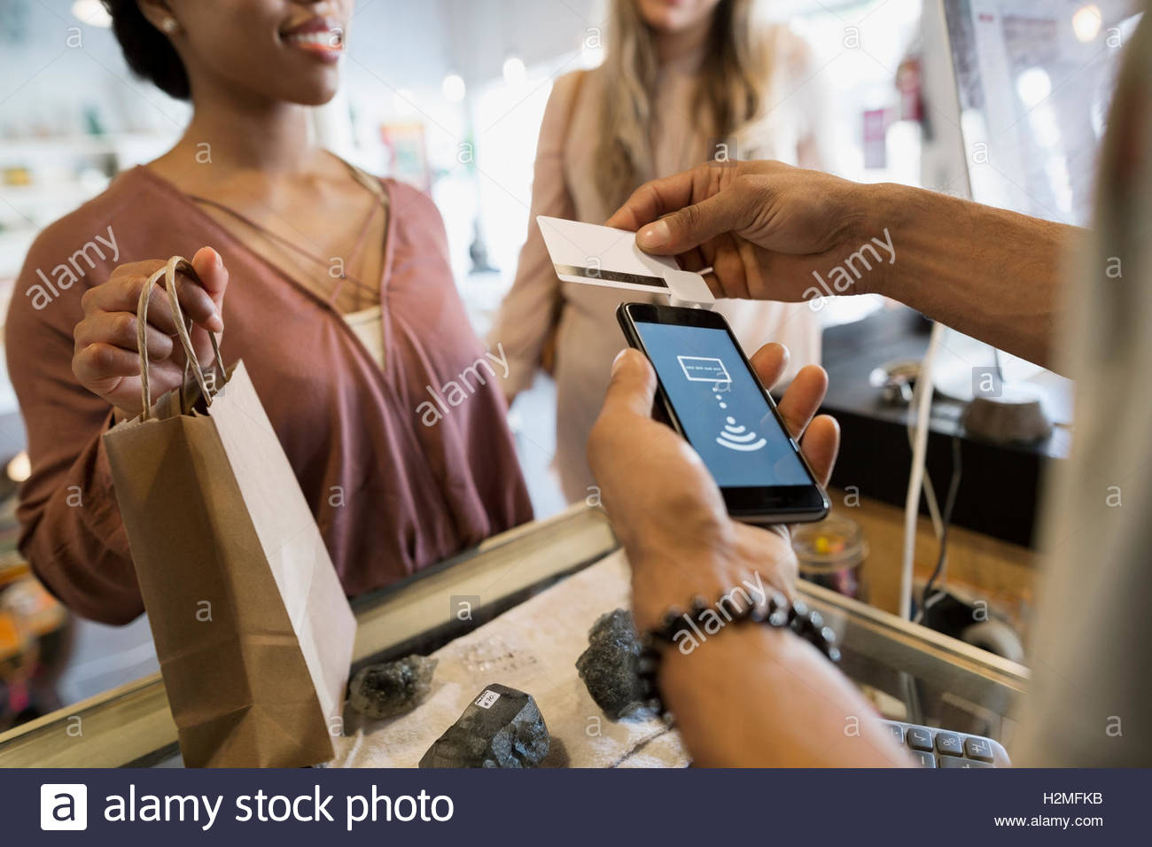 Customers paying shop owner using contactless payment cell phone credit ...