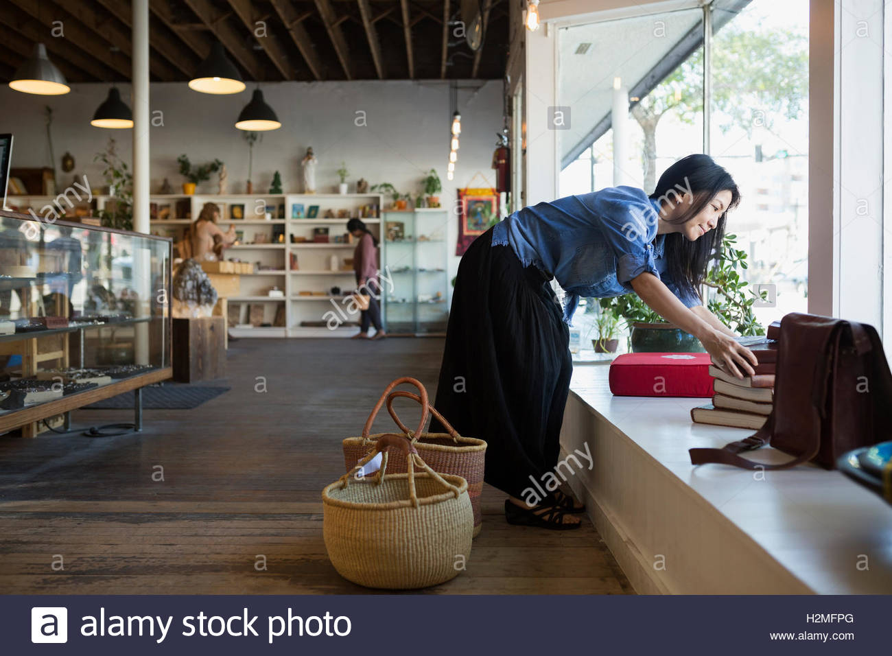 Female shop owner arranging books in window display Stock Photo - Alamy