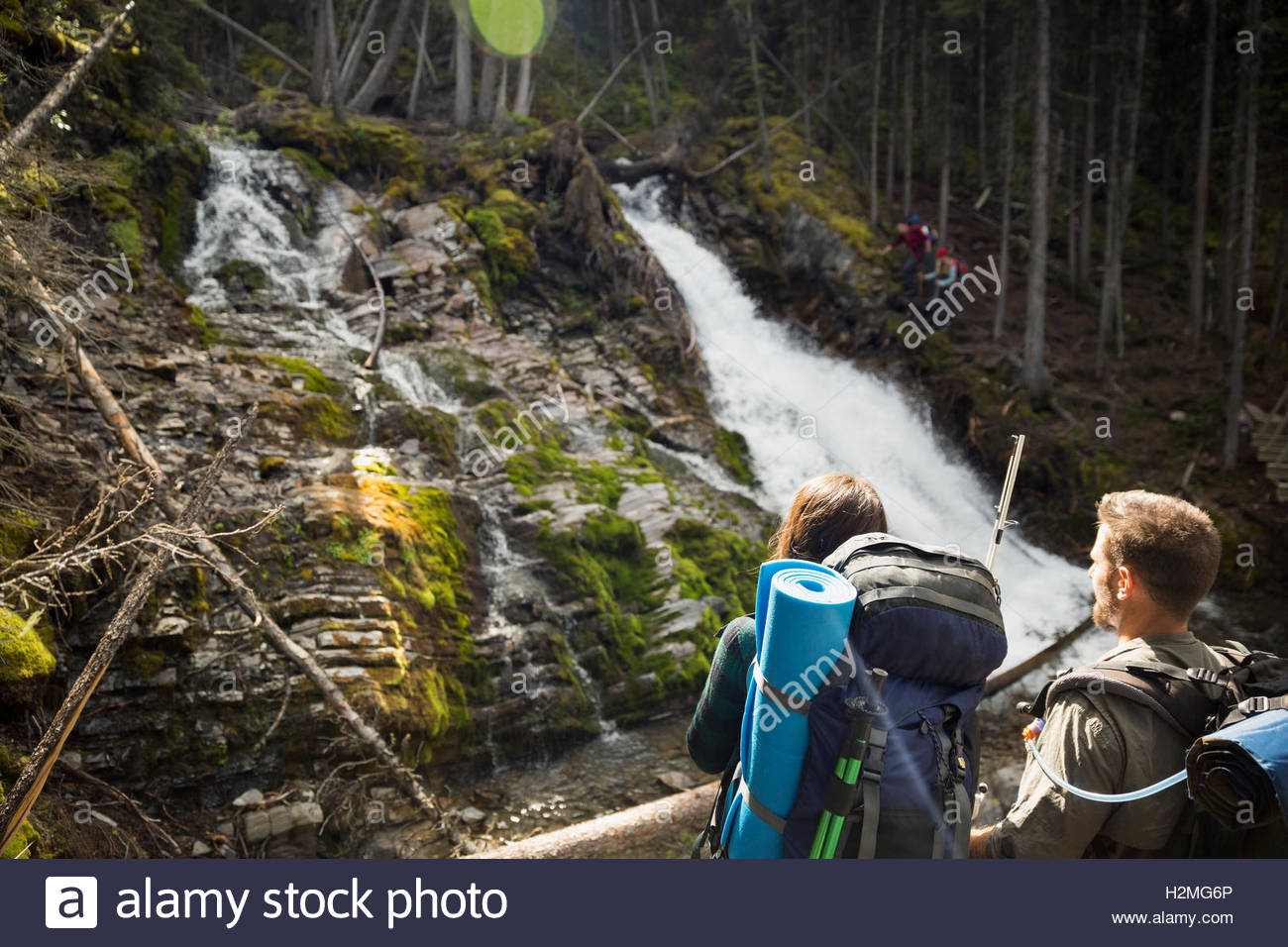 Couple hiking with backpacks enjoying waterfall view in woods Stock ...