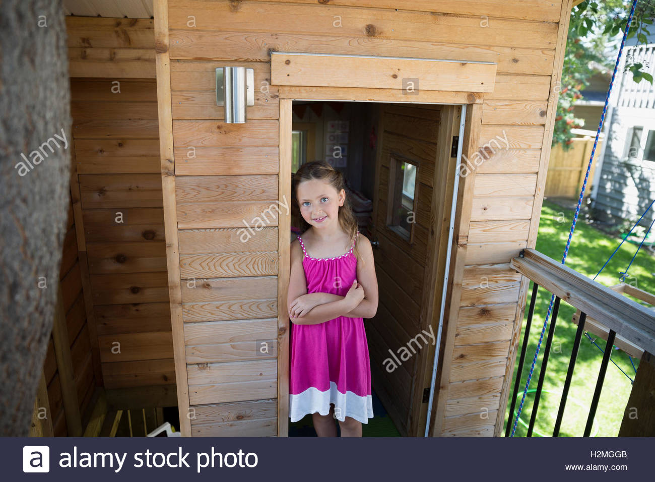 Portrait smiling girl in pink dress in treehouse doorway Stock Photo ...