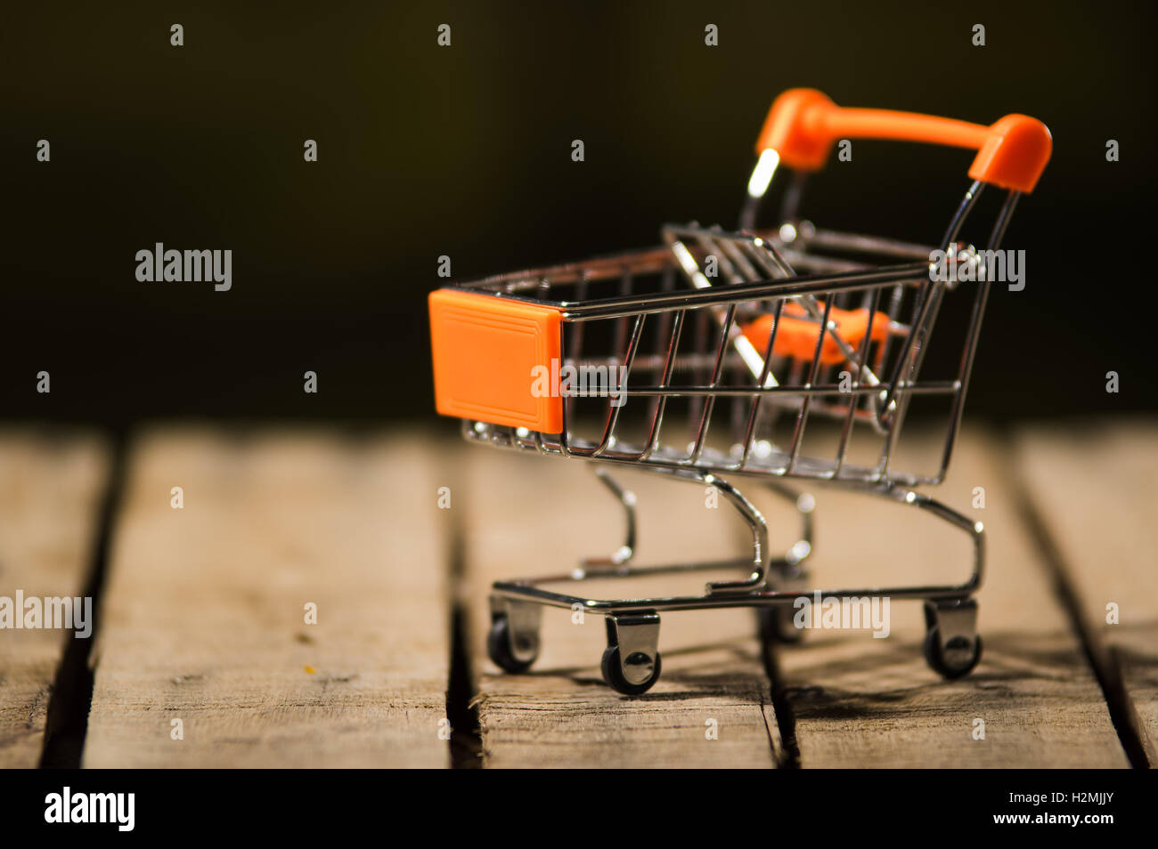 Miniature shopping trolley sitting on wooden surface, magicians concept ...