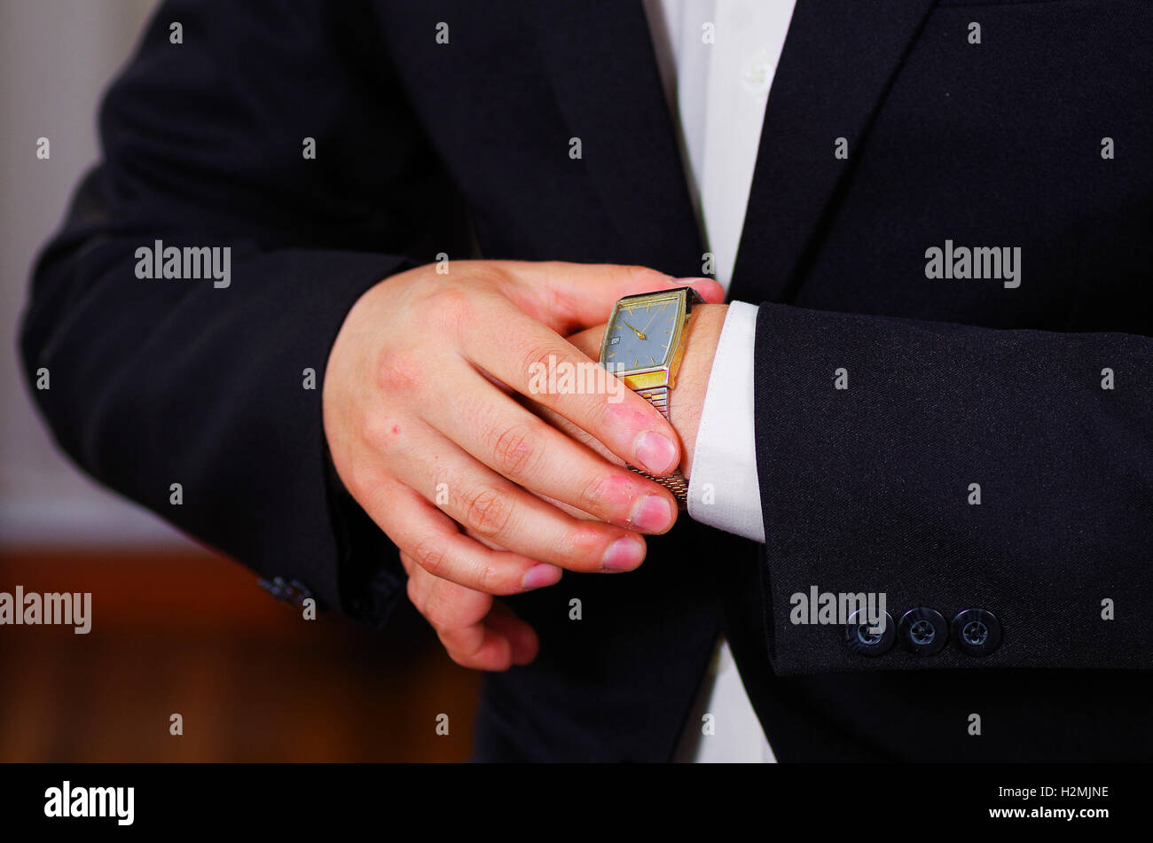 Closeup man's arm wearing suit, adjusting silver wrist watch using ...