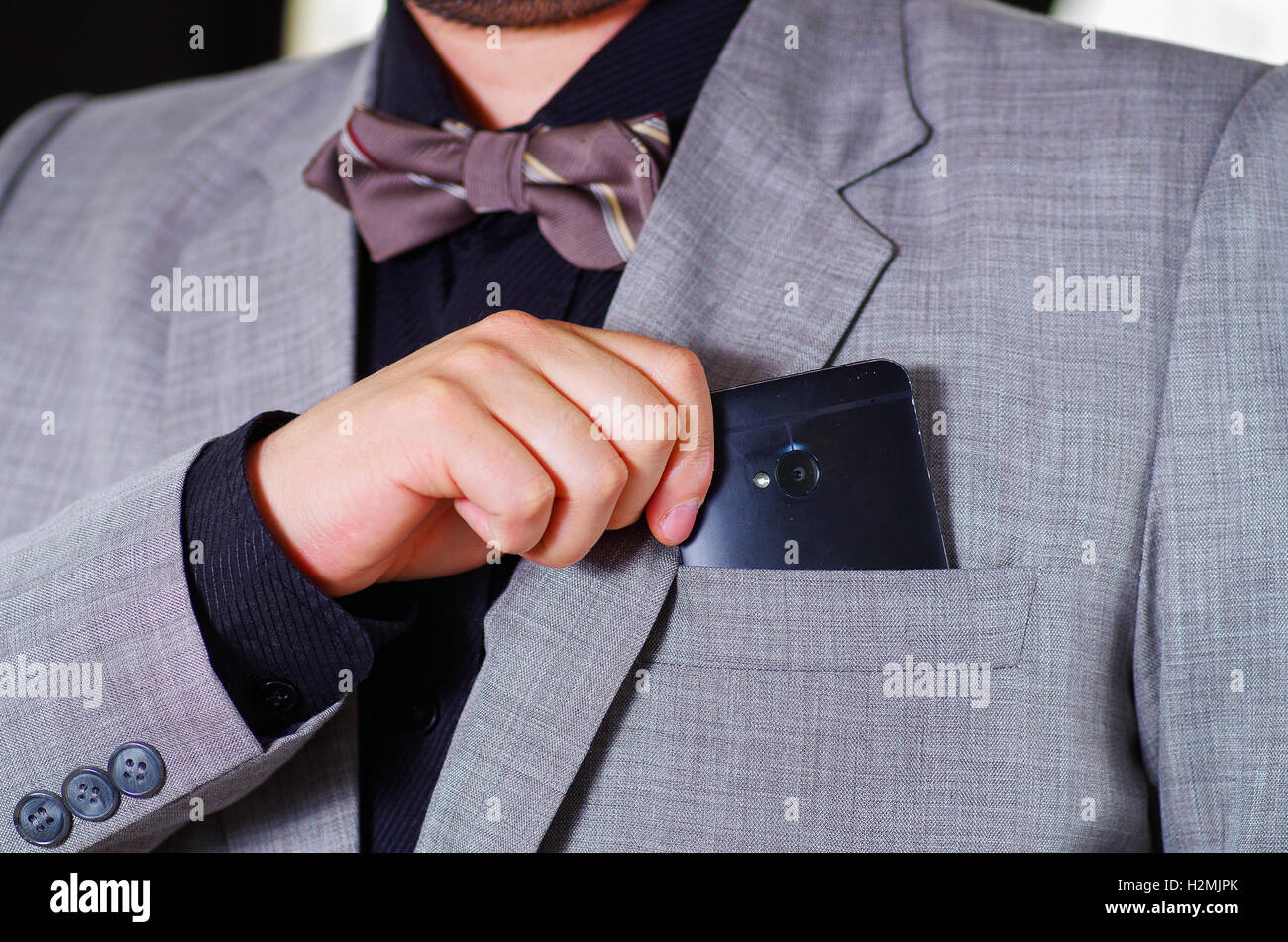 Closeup man's chest area wearing formal suit and tie, placing phone in ...
