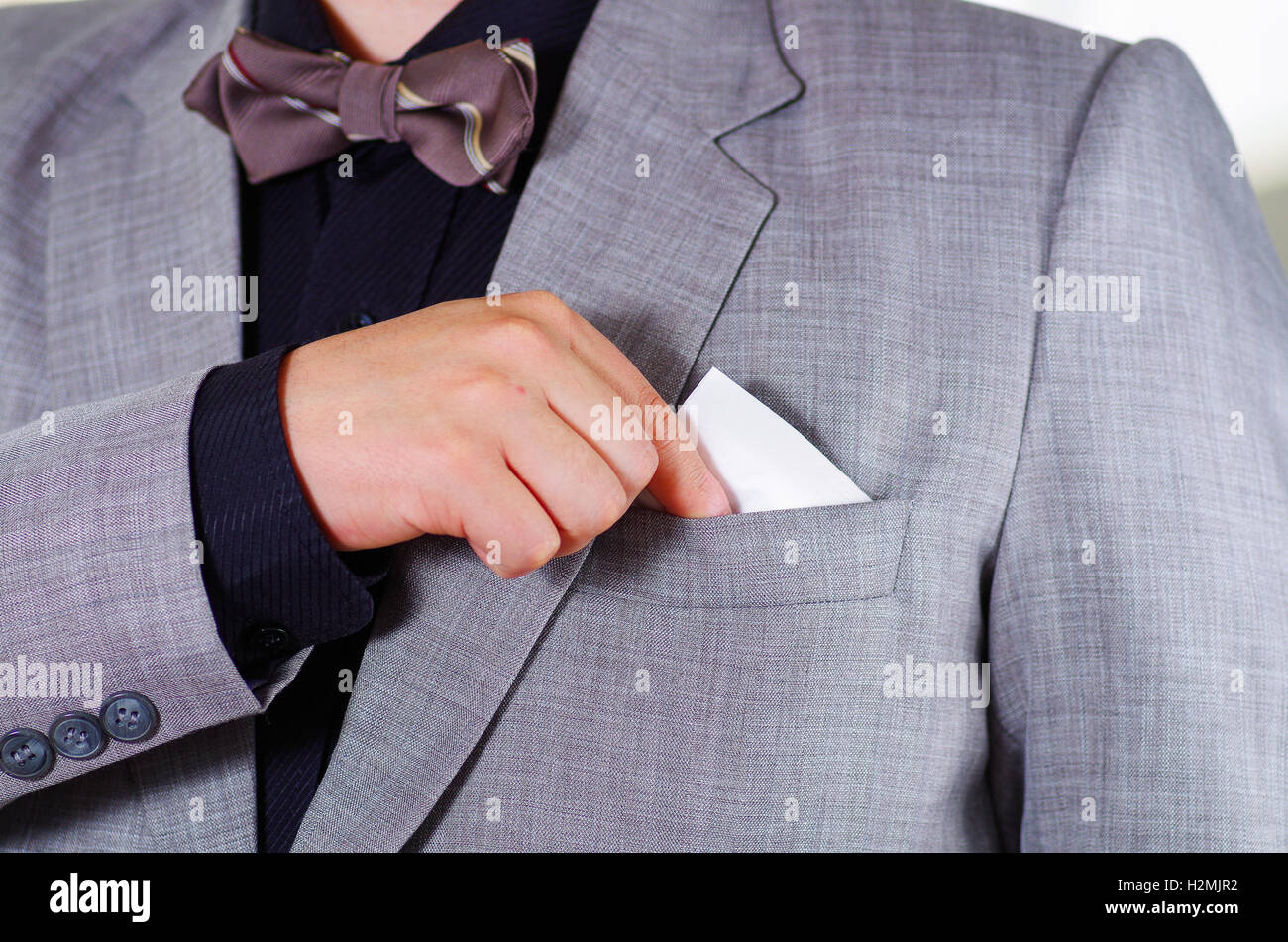 Closeup man's chest area wearing formal suit and tie, placing tissue in ...