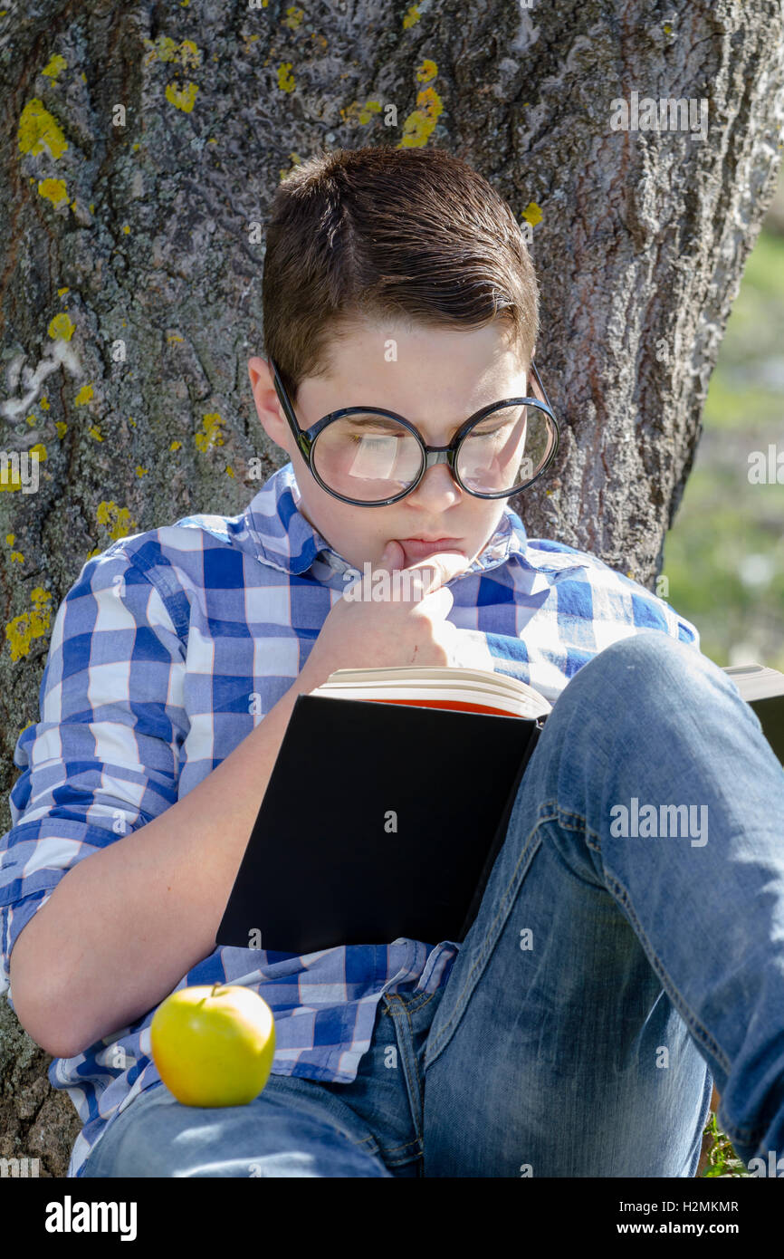 Young boy reading a book in the woods with shallow depth of fiel Stock ...